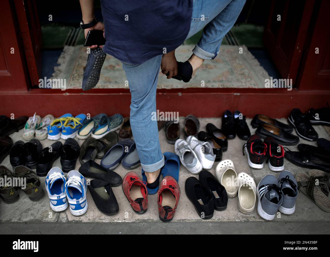 A Chinese Muslim takes off his shoes before entering a prayer hall to ...