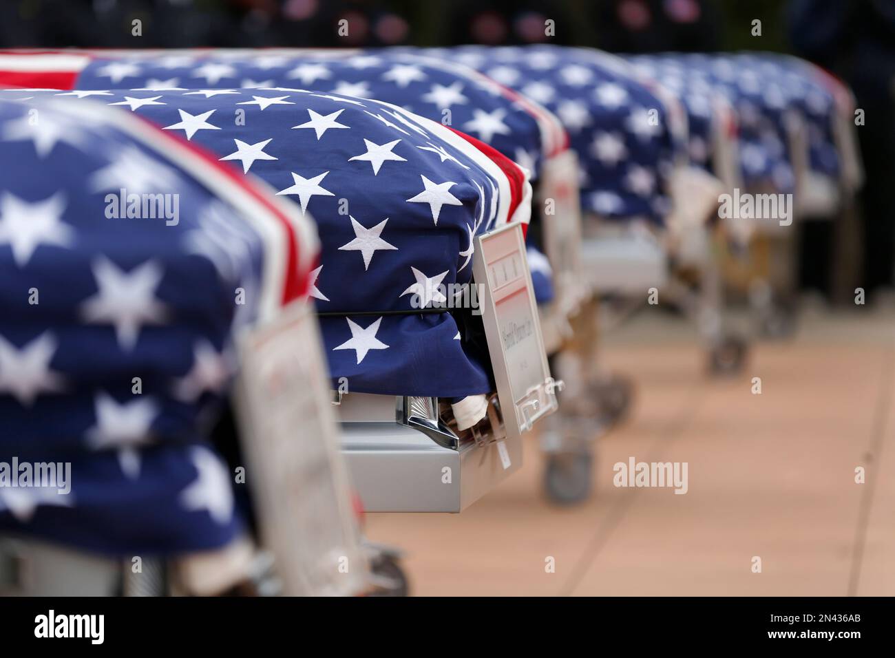 Flag draped caskets are shown lined up at a memorial service and burial ...