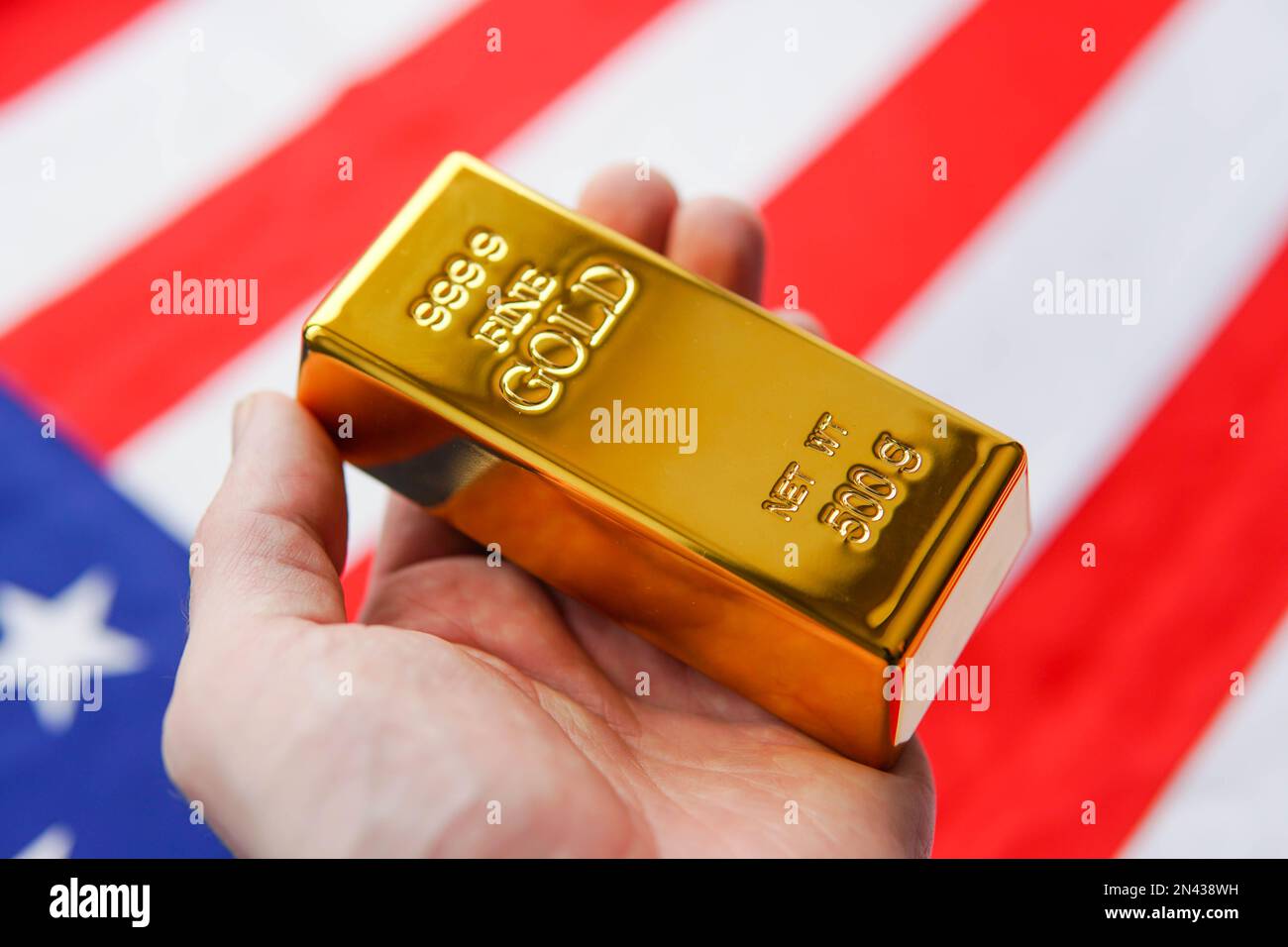 The gold bar in man's hand on the national flag of USA background. Gold ...