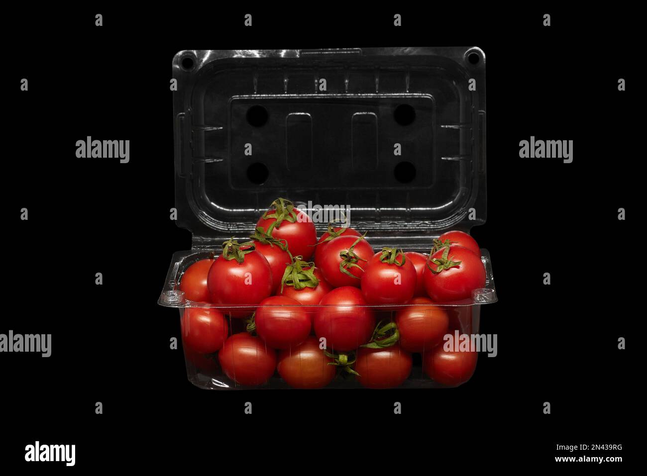 Image of small tomatoes in plastic packaging on a black background ...