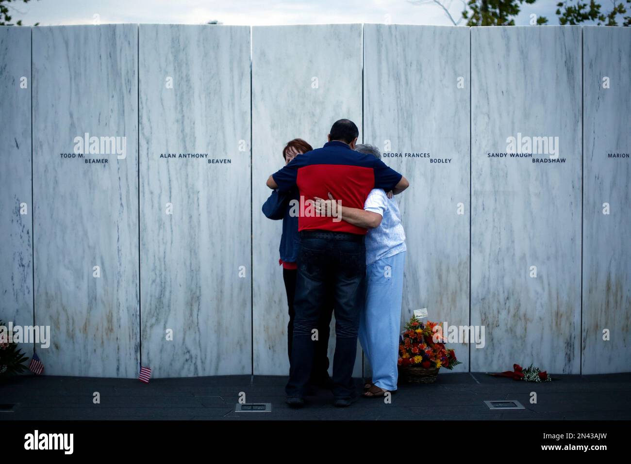 Rick Sarmiento, center, hugs Karen Bingham, left, and Nancy Root, right ...
