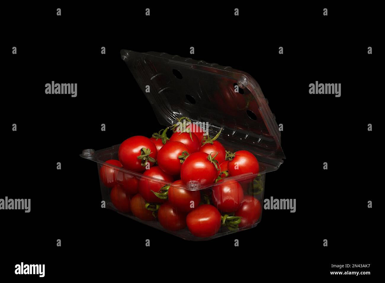 Image of small tomatoes in plastic packaging on a black background ...