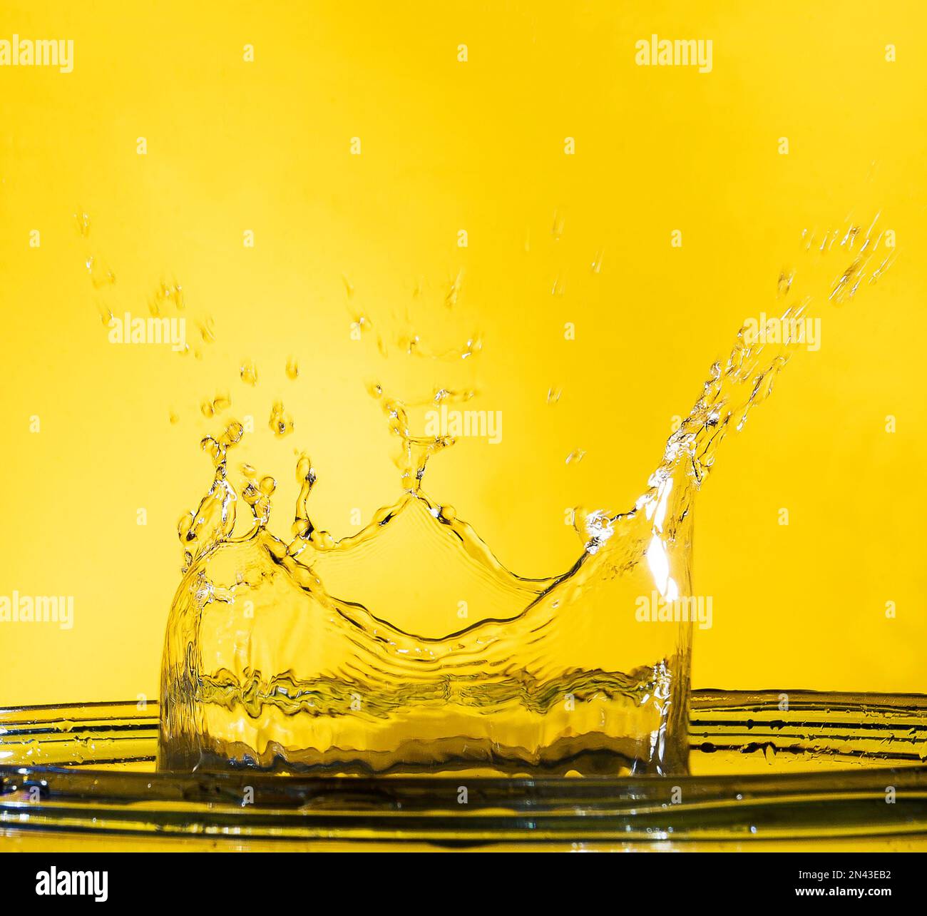 Water splash on bright glowing yellow background Stock Photo - Alamy