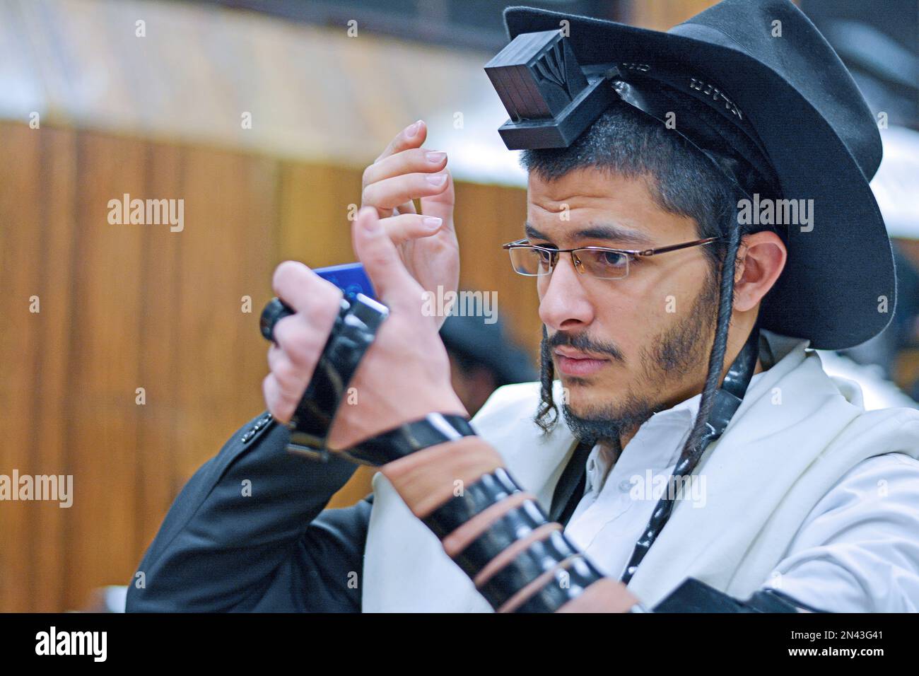 An young orthodox jewish man adjusts his head tefillin to be sure it's ...