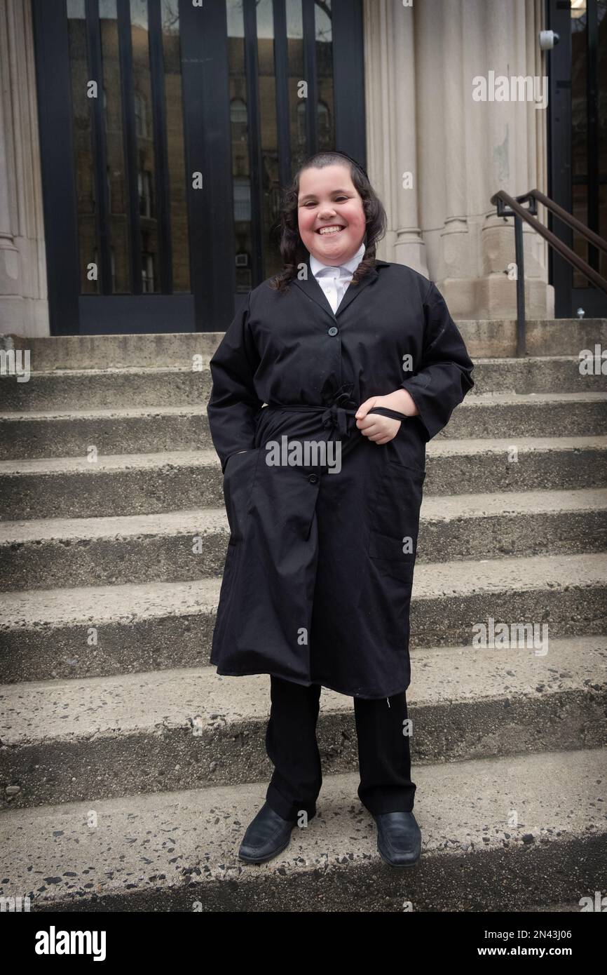 Posed portrait of a smiling Hasidic Jewish teenager on the steps of his ...