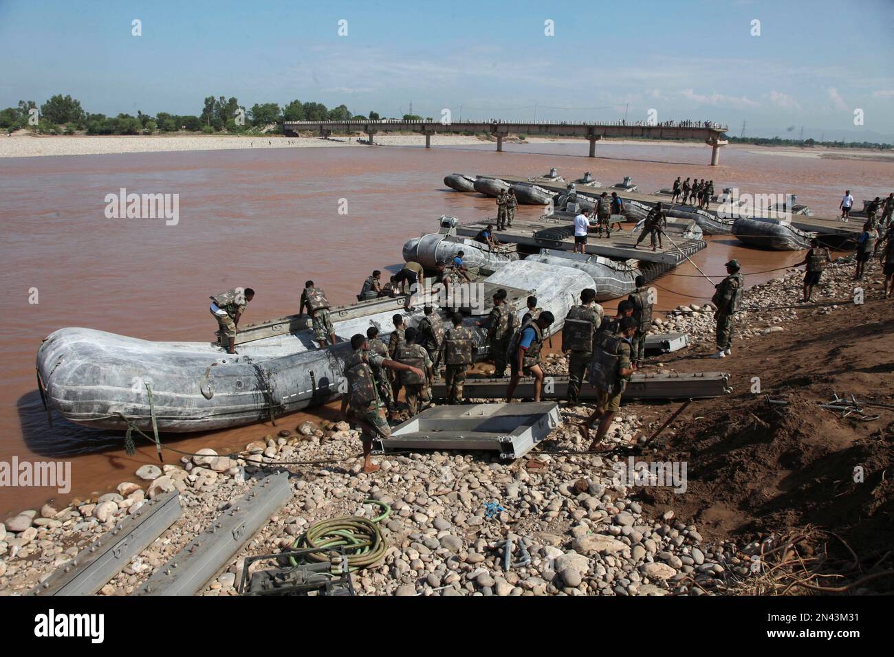 Indian army soldiers build a temporary bridge across the Tawi River ...
