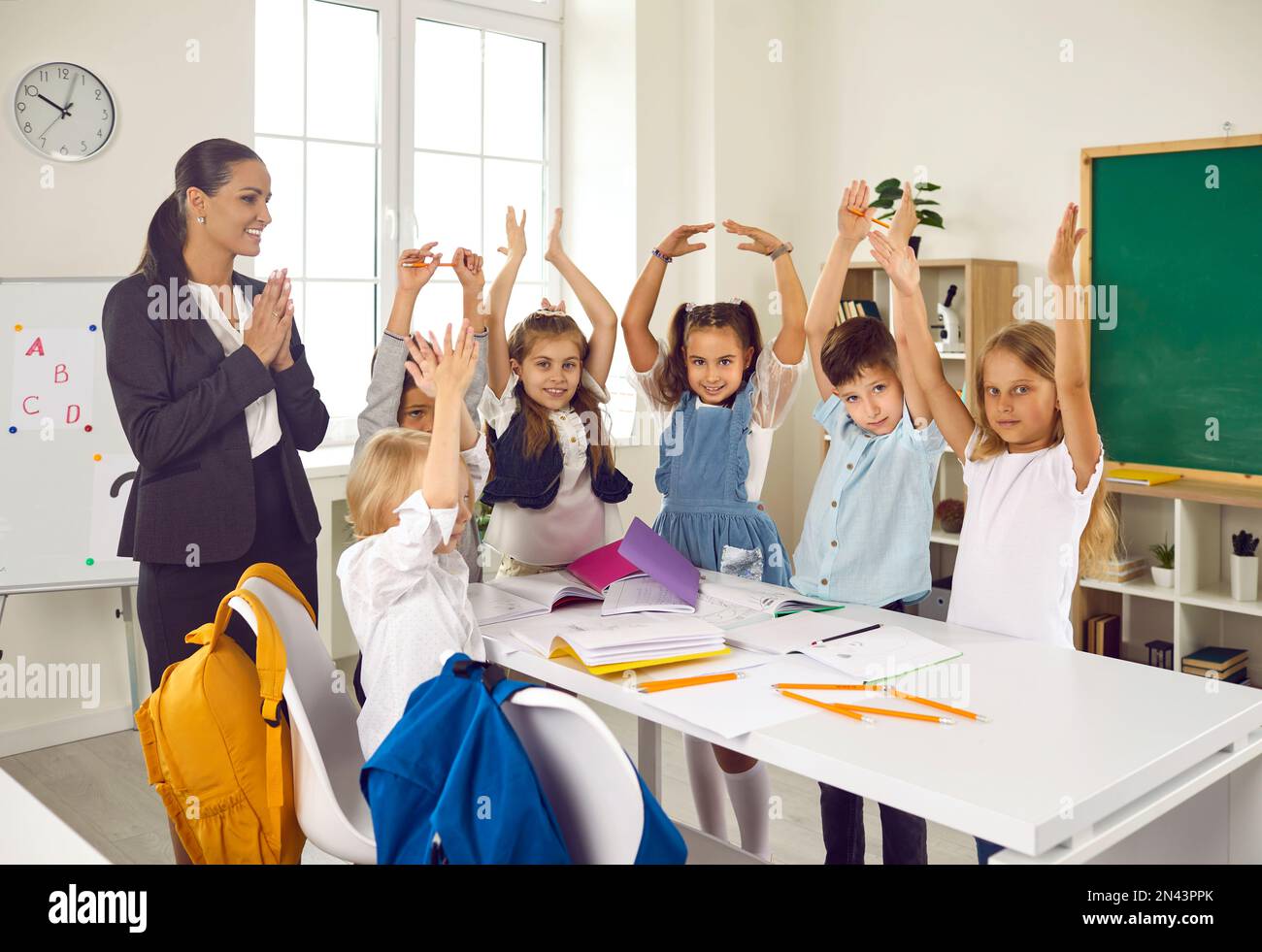 Group of happy school children standing by table in classroom and ...