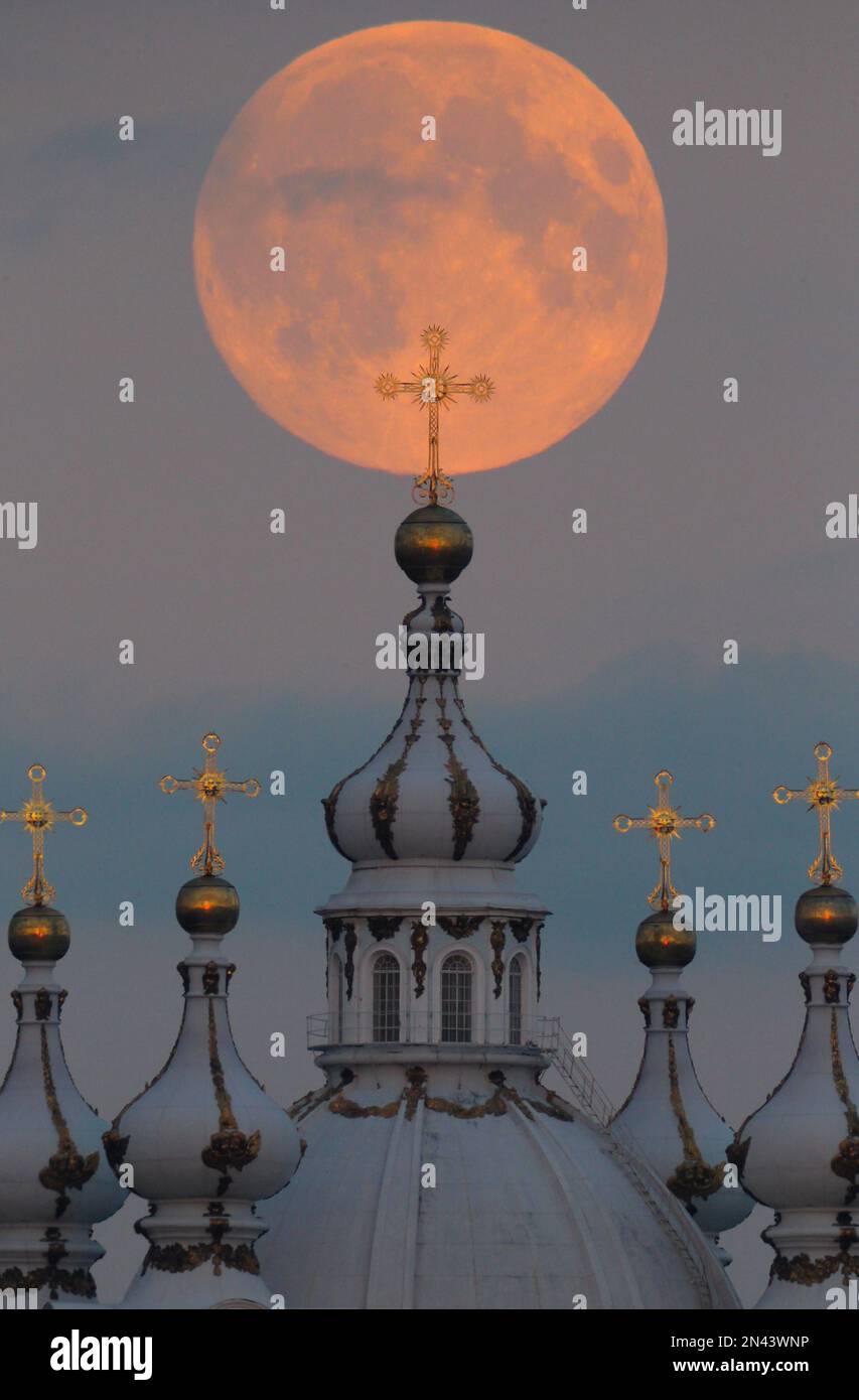 The full moon is seen rising in the sky above the domes of the Smolny ...