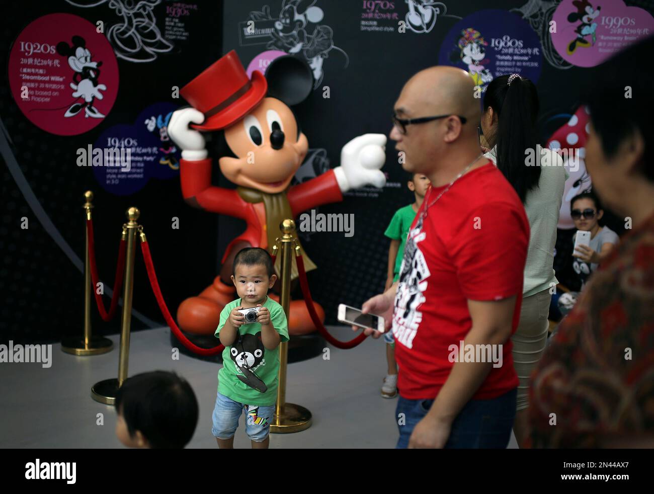 A Chinese child holds a camera as others take souvenir pictures near a ...