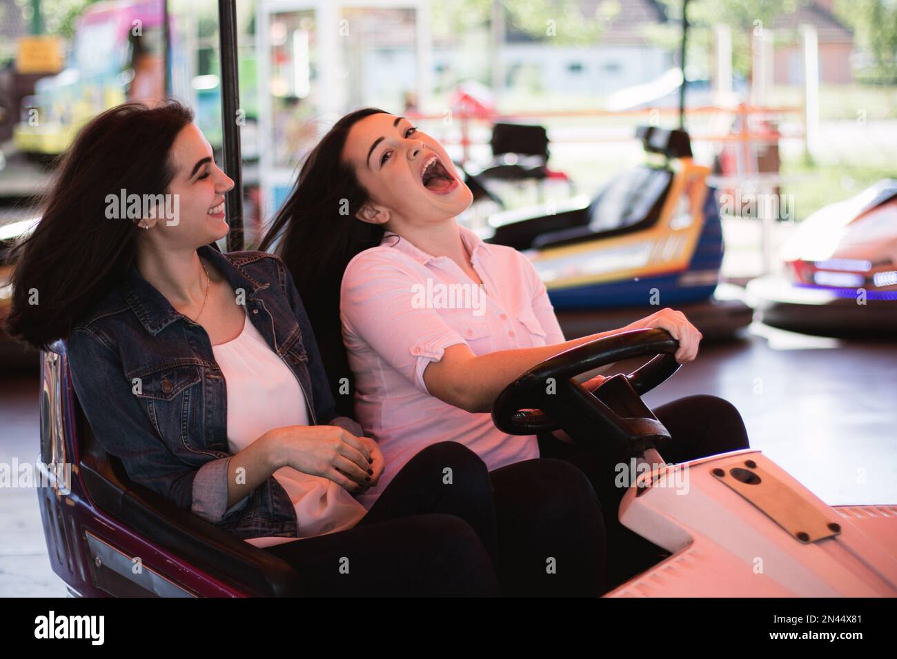 Two young women having a fun bumper car ride at the amusement park ...