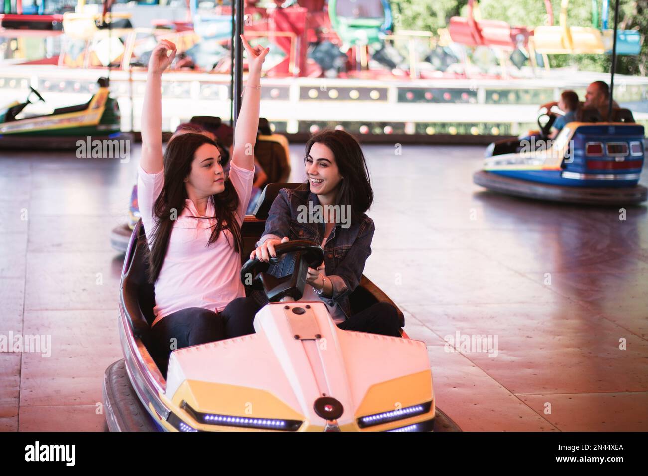 Two young women having a fun bumper car ride at the amusement park ...