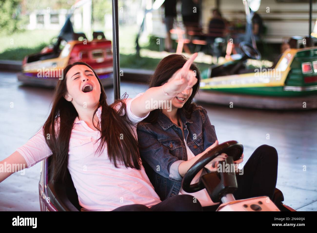Two young women having a fun bumper car ride at the amusement park ...