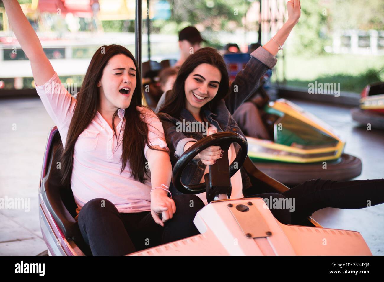 Two young women having a fun bumper car ride at the amusement park ...