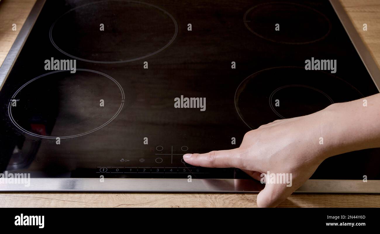 A woman's finger presses the inclusion of a modern induction hob in the ...