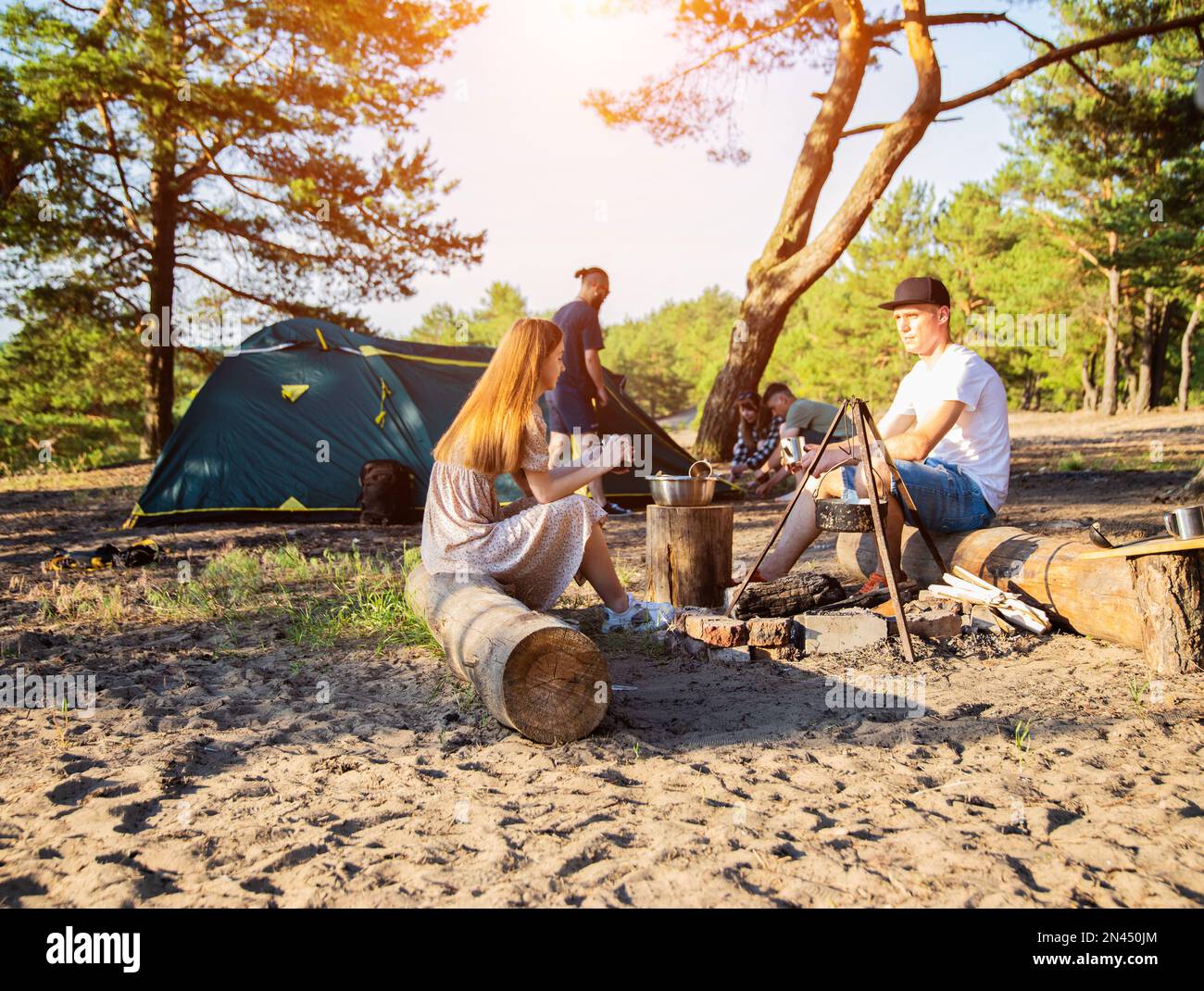 A guy and a young girl sit on a log in nature and talk against the ...
