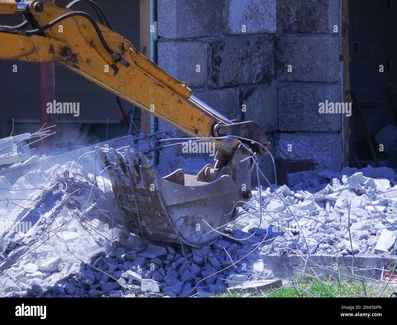 Bucket of a hydraulic excavator collects the rubble after a demolition ...
