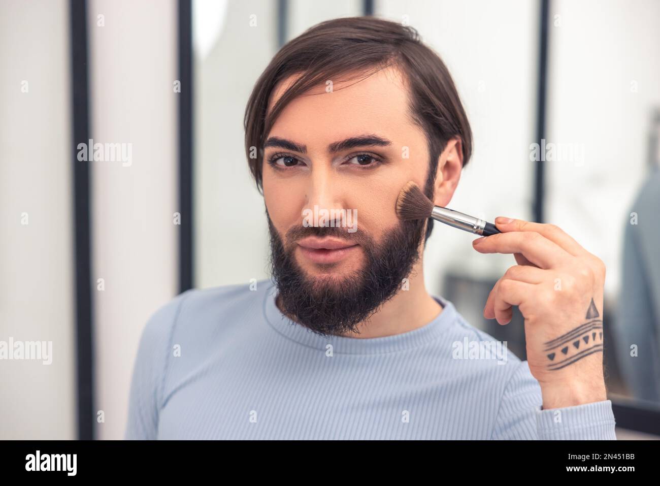 Transgender person powdering the face indoors Stock Photo - Alamy