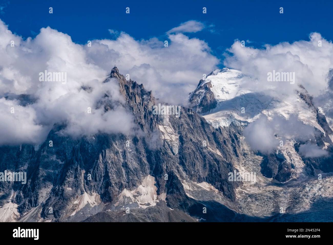 The summits of Aiguille du Midi and Mont Blanc du Tacul sticking out of the clouds, seen from Le ...