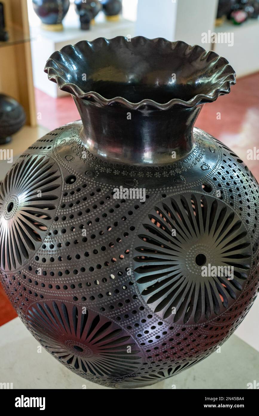 A Oaxacan black ceramic pot with an elaborate cut-out design in a shop ...