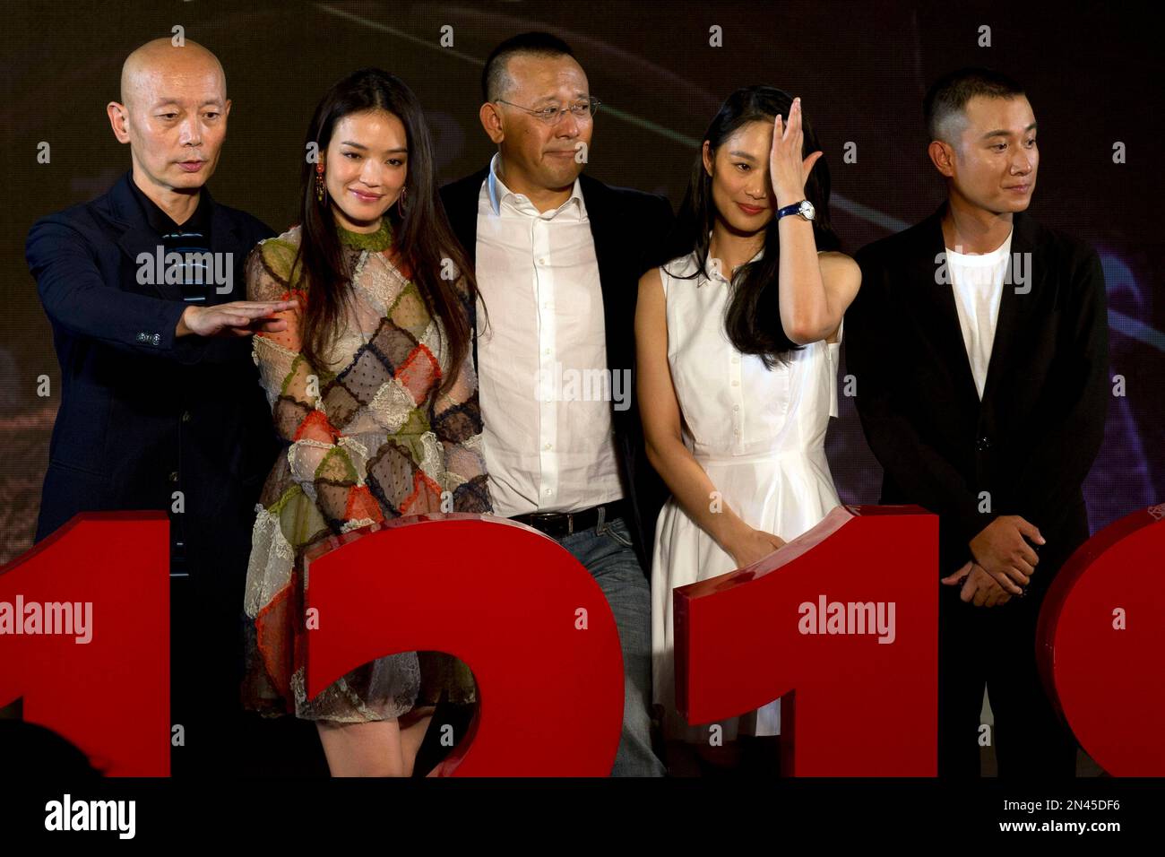 Chinese director Jiang Wen, center, poses for photos near cast members from right Wen Zhang ...