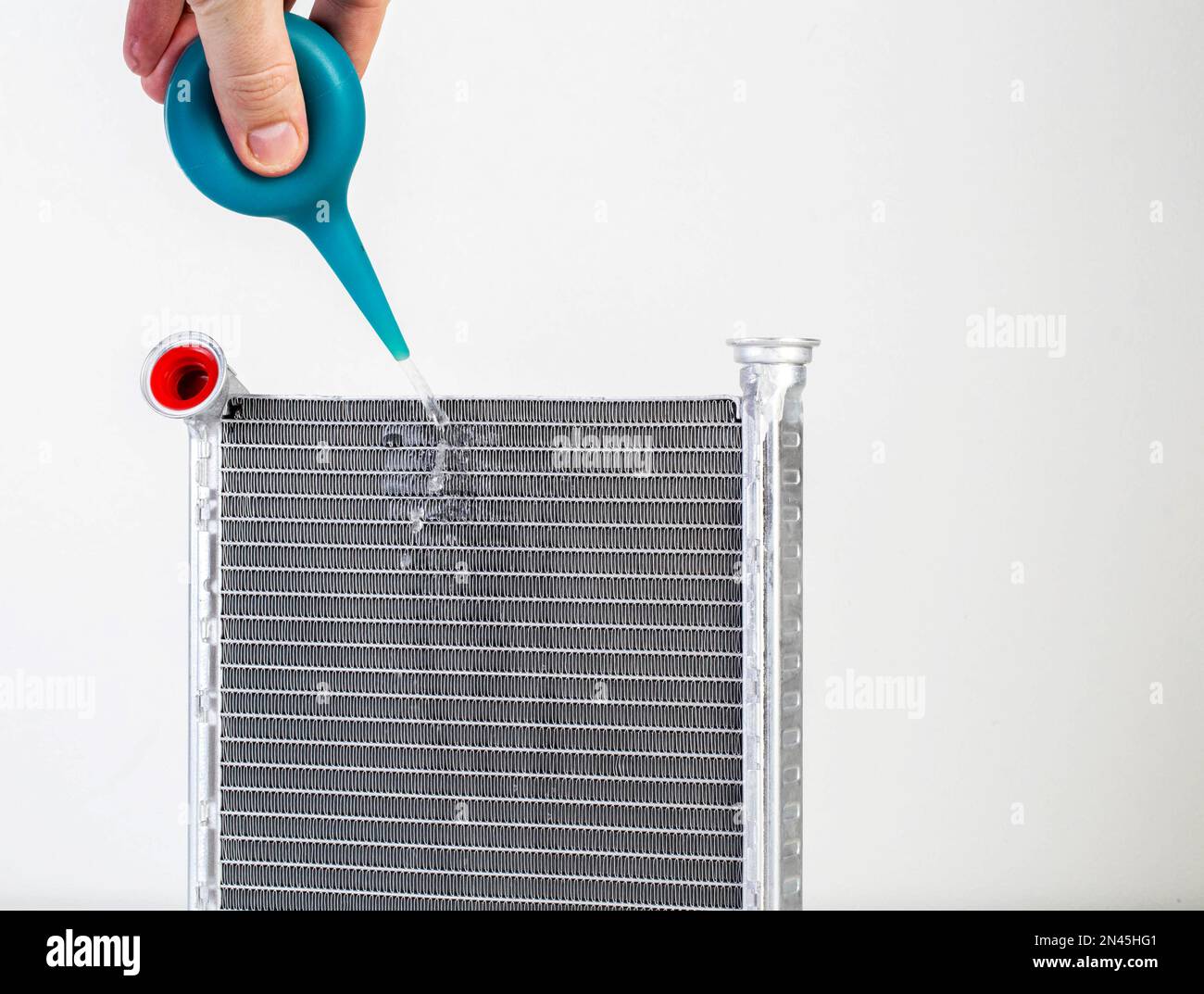 A jet of water from a syringe pours onto a car radiator. The concept of ...