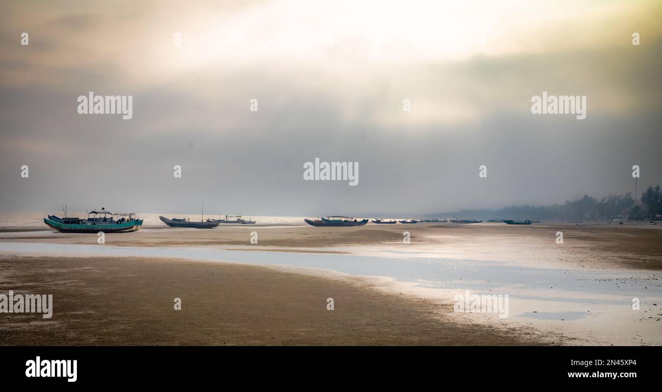 Traditional wooden fishing boats stranded at low tide in the mist on ...