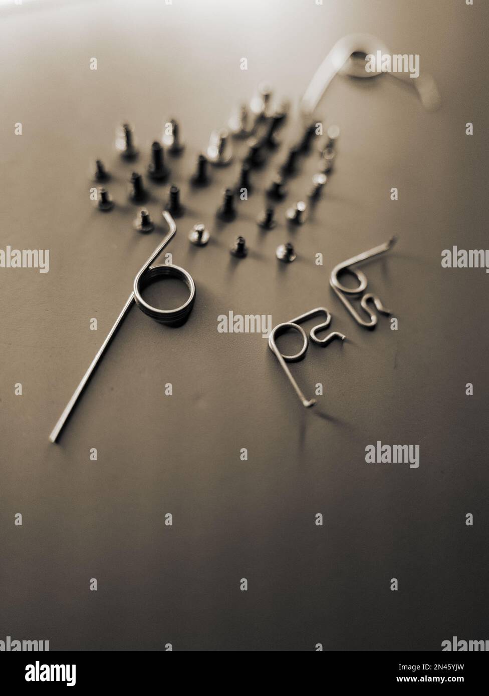 A vertical grayscale of screws and bolts in the shape of a heart on an ...