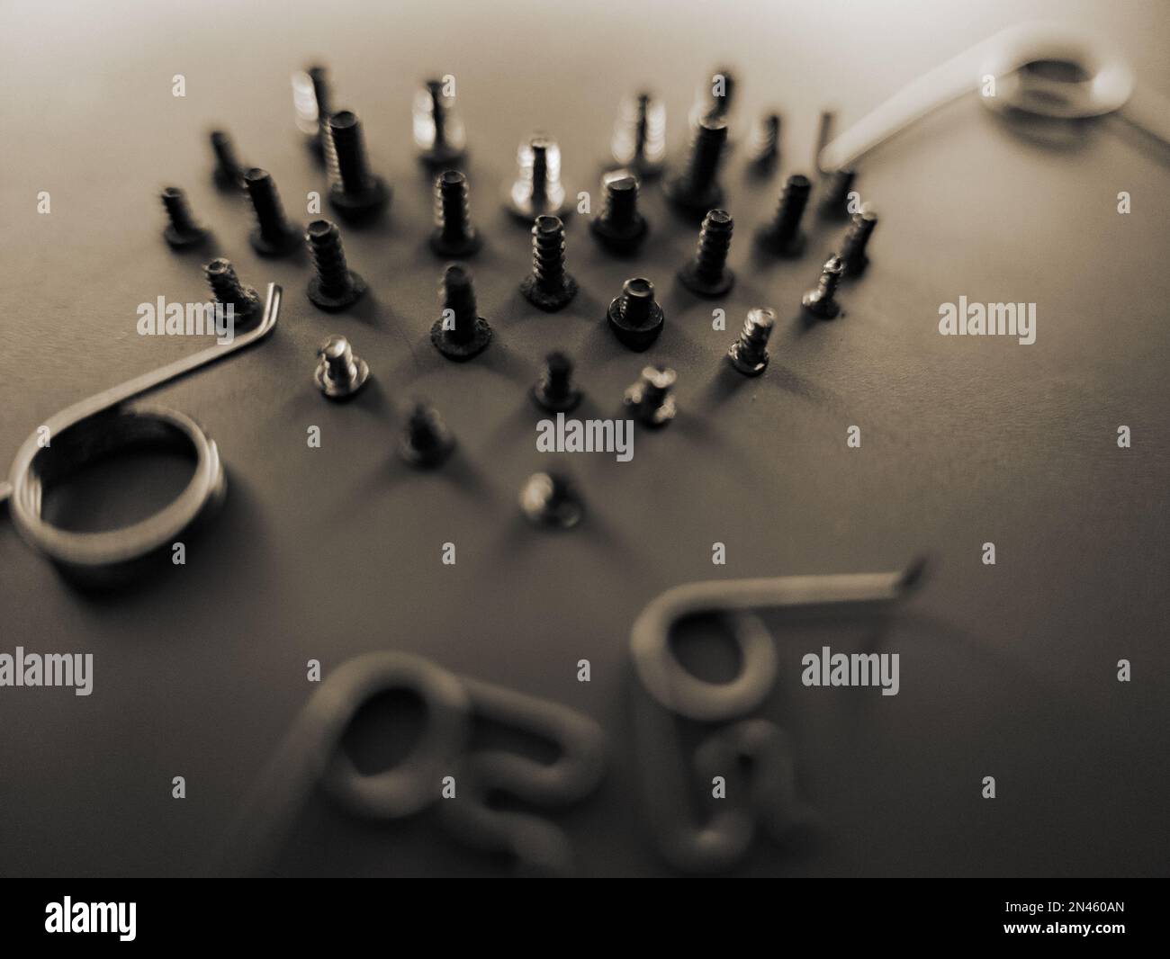 A closeup grayscale of screws and bolts in the shape of a heart on an ...