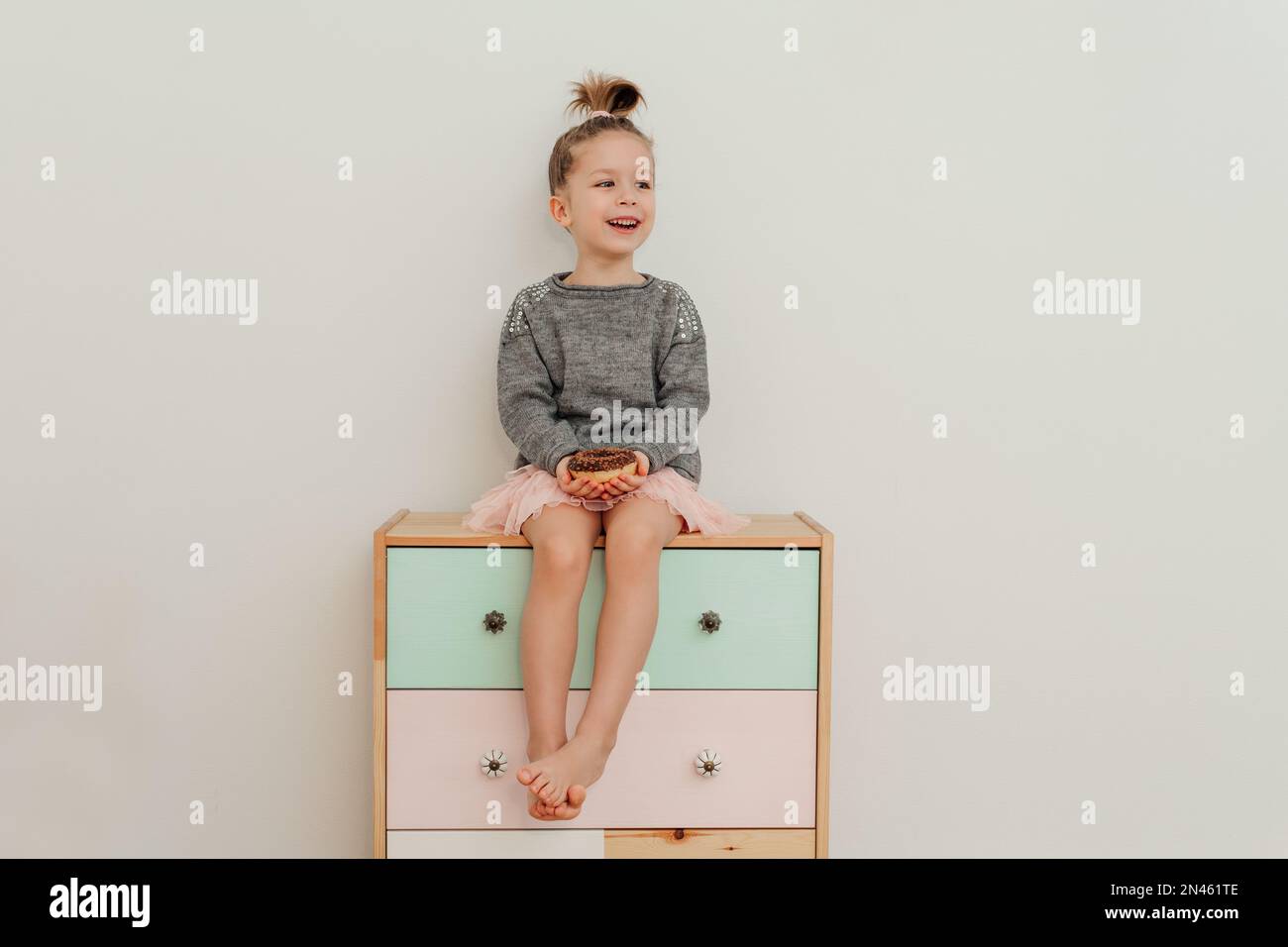 Funny little girl with modern hairstyle is sitting on the commode with ...