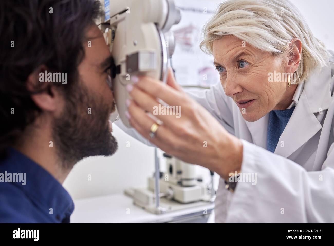Doctor with a man in vision test or eye exam for eyesight by a focused ...