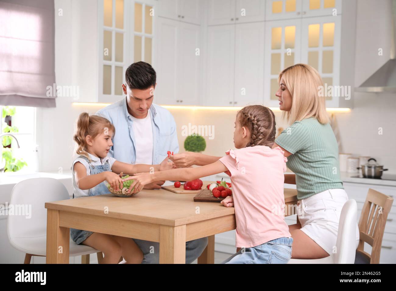 Happy family cooking together at table in modern kitchen Stock Photo ...