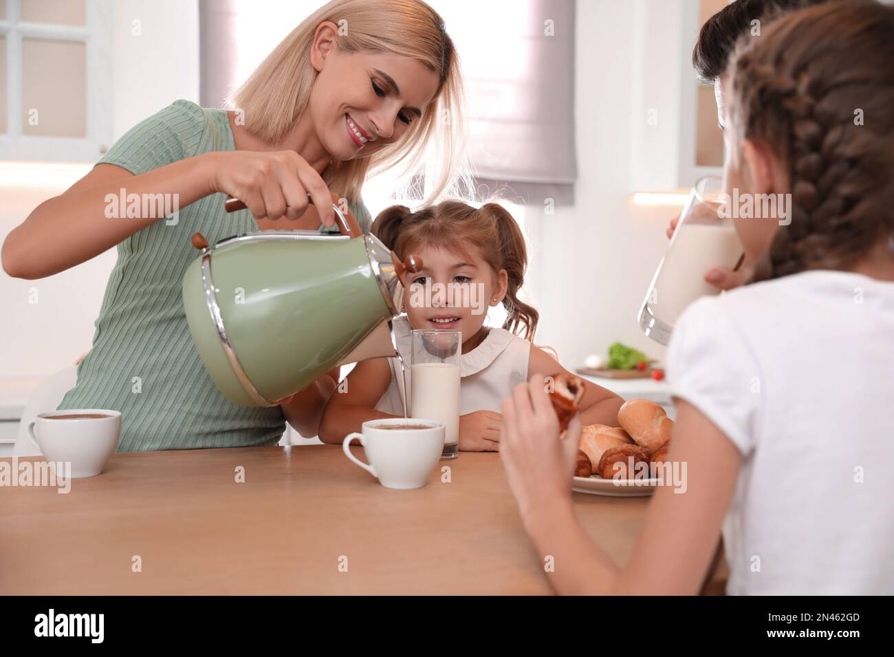 Happy family eating together at table in modern kitchen Stock Photo - Alamy