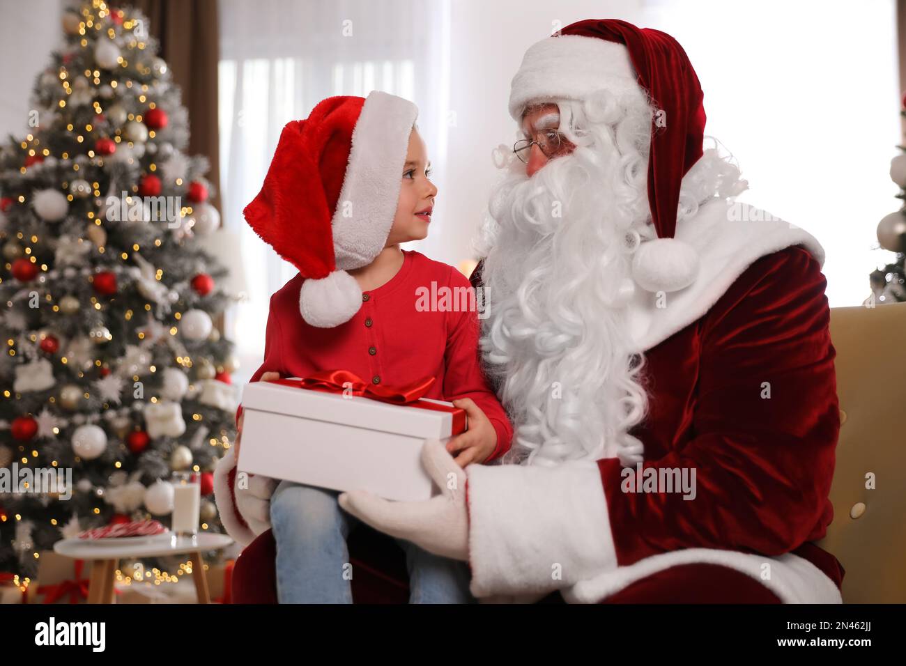 Santa Claus giving present to little girl in room decorated for ...