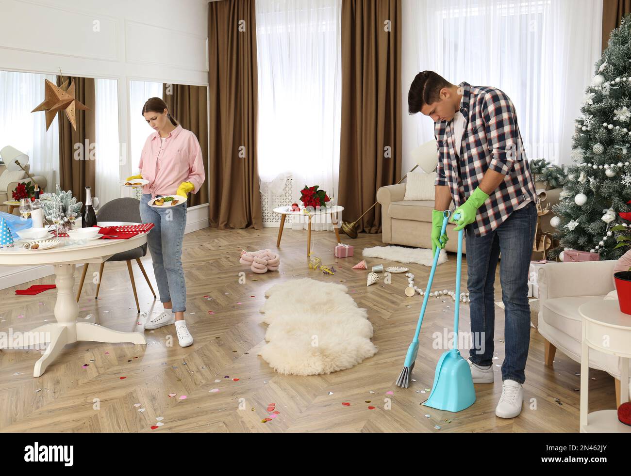 Couple cleaning messy room after New Year party Stock Photo - Alamy