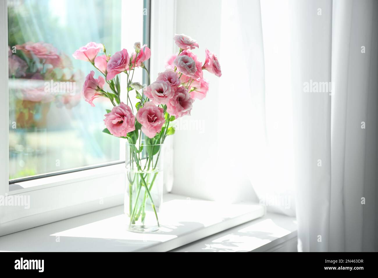 Glass vase with beautiful flowers on window sill in room, space for ...