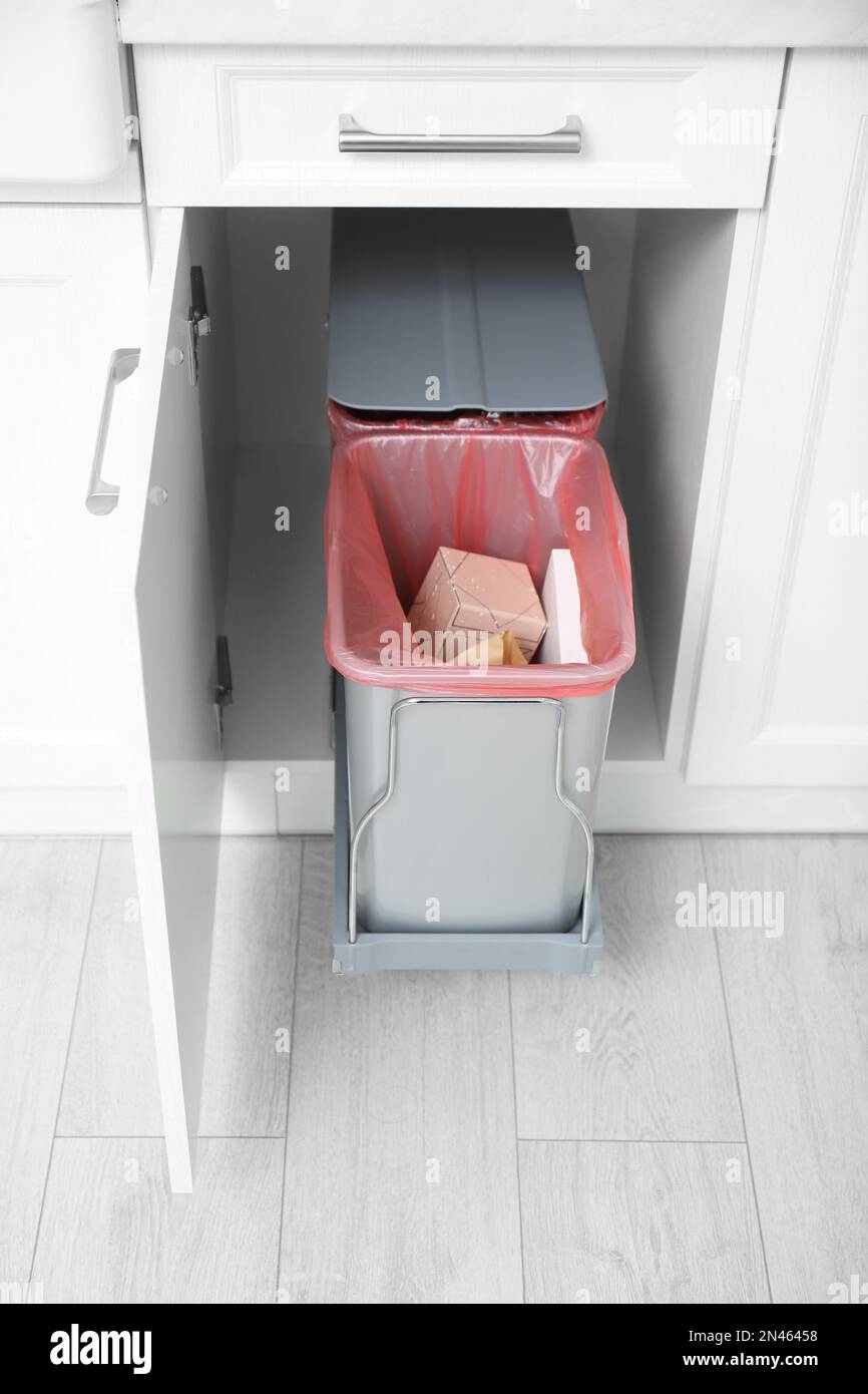 Open cabinet with full trash bin in kitchen Stock Photo - Alamy