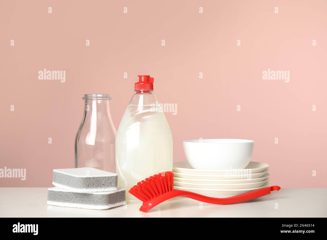 Cleaning supplies for dish washing and plates on white table against ...