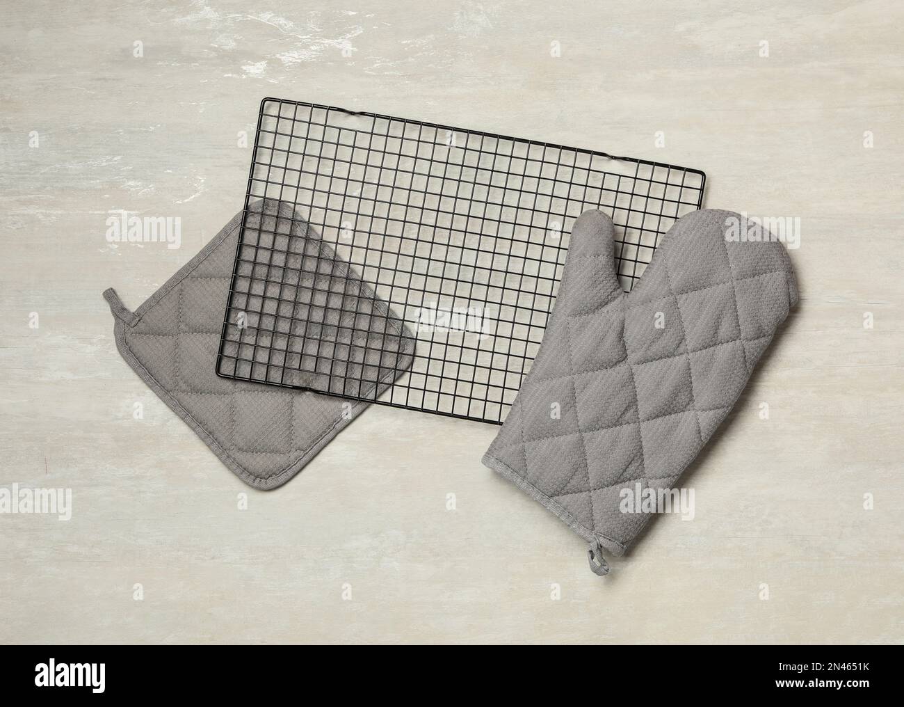 Oven mitt, potholder and cooling rack on grey table, flat lay. Cooking ...