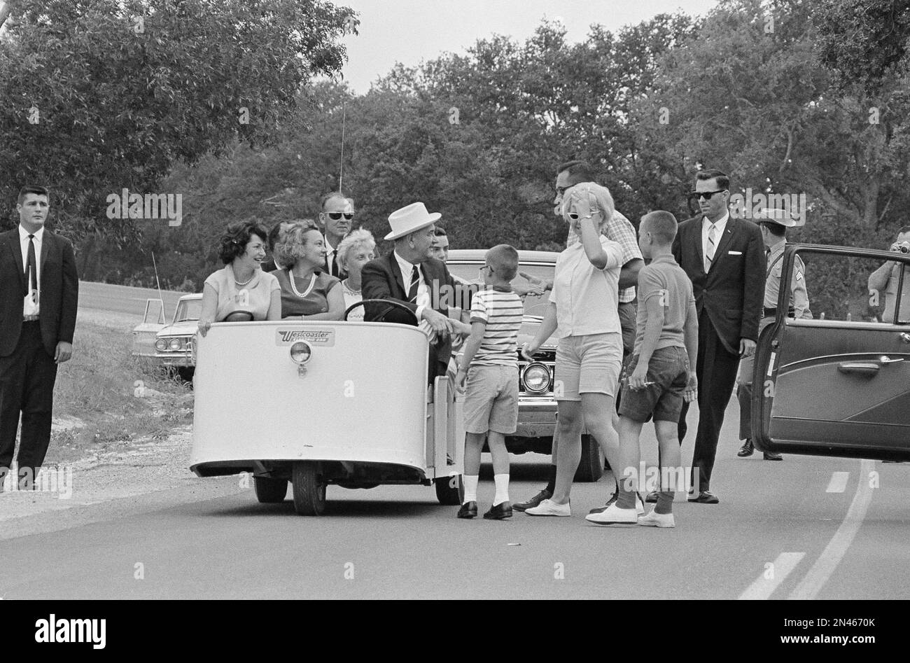 Using both hands, President Lyndon B. Johnson shakes hand with tourists ...
