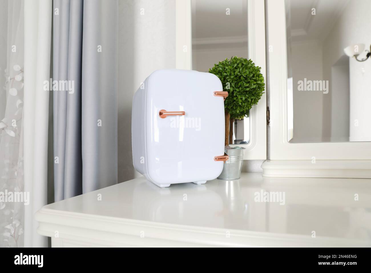 Mini fridge for cosmetic products on white vanity table Stock Photo - Alamy
