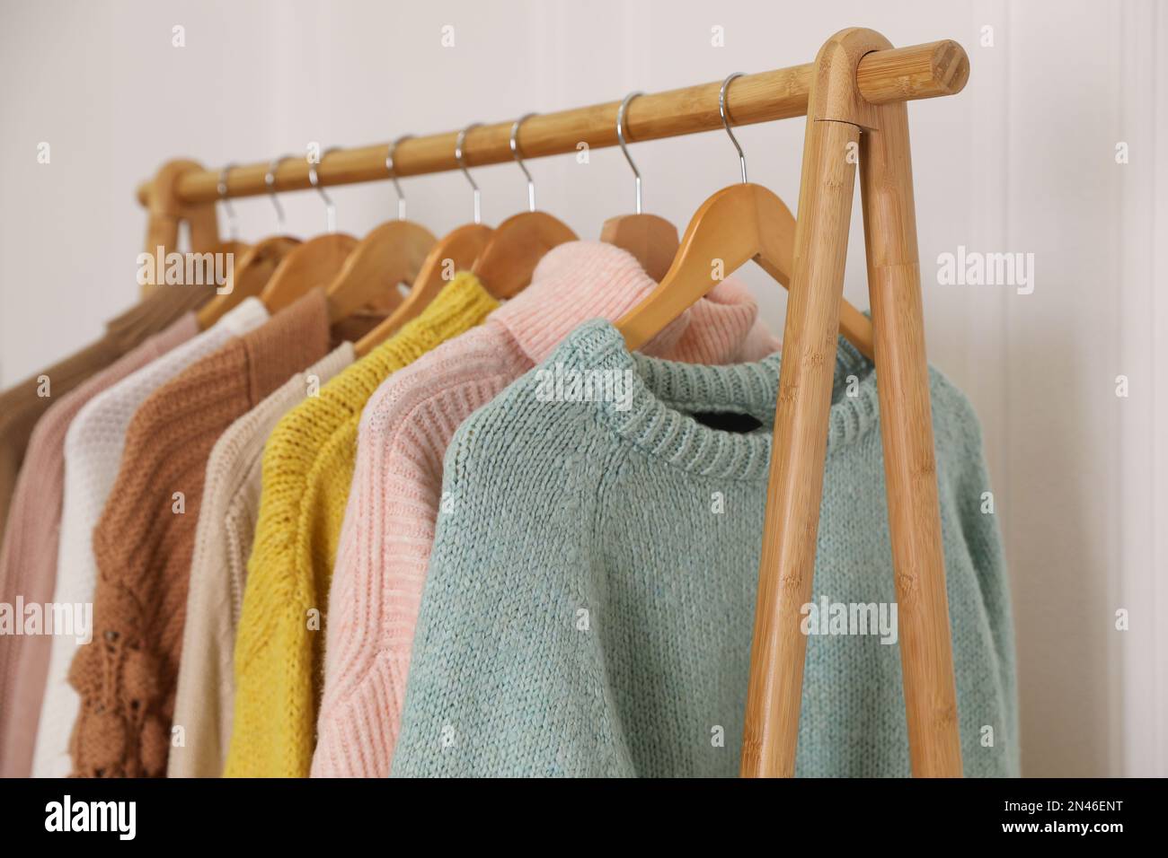 Different stylish warm clothes on rack indoors Stock Photo - Alamy