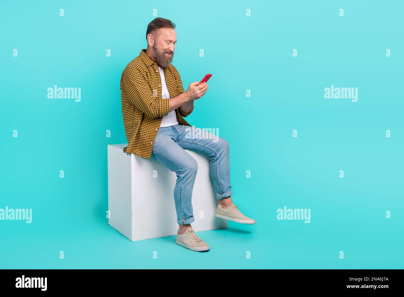 Photo of attractive man addicted user sitting cube hold modern device ...