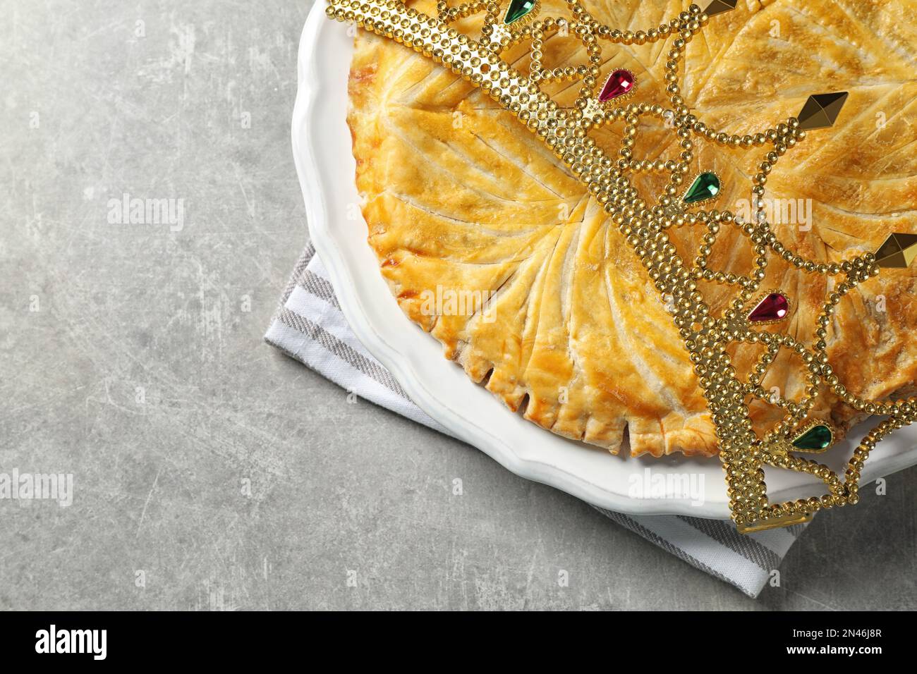 Traditional galette des Rois with decorative crown on light grey table ...