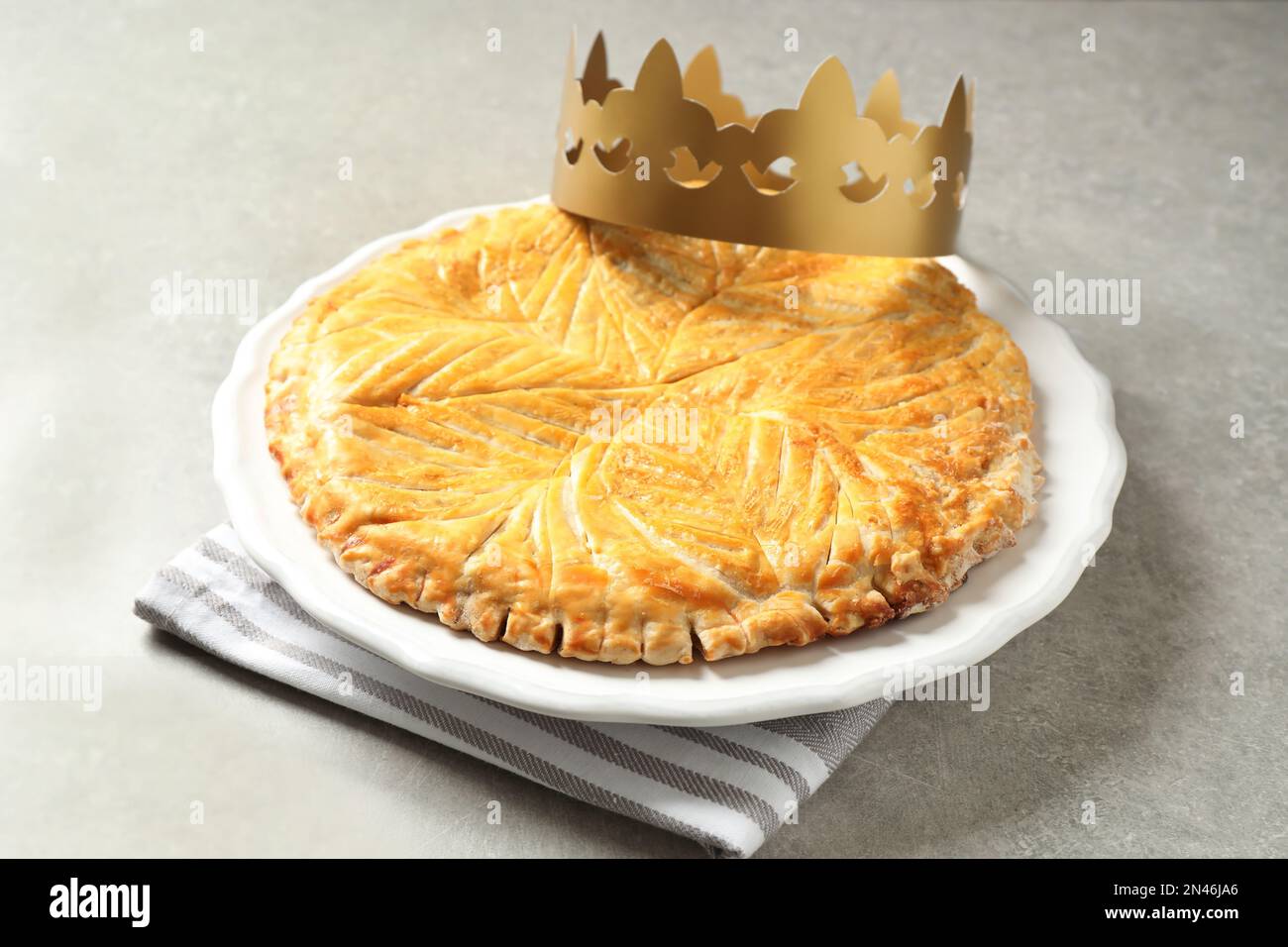Traditional galette des Rois with paper crown on light grey table Stock ...