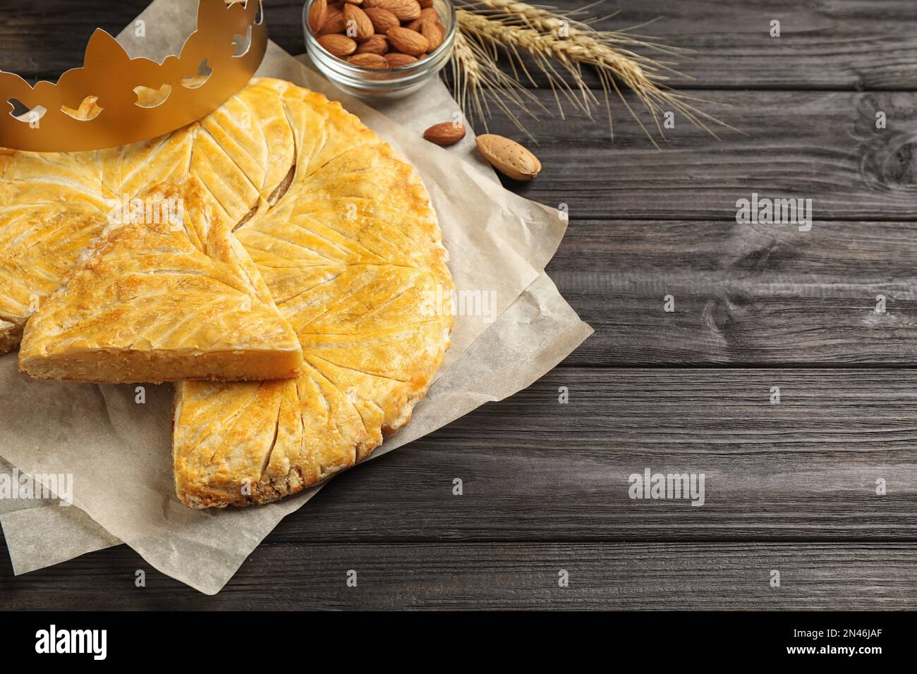 Traditional galette des Rois with paper crown on black wooden table ...