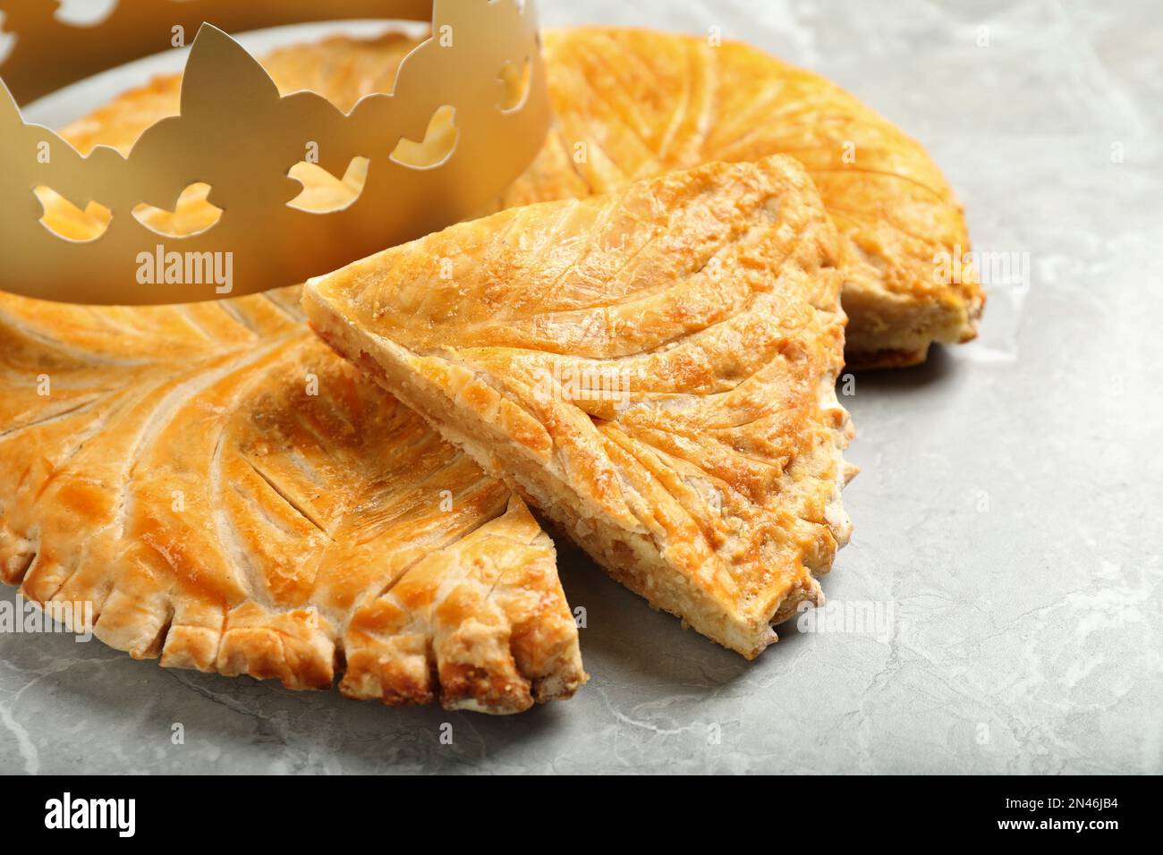 Traditional galette des Rois with paper crown on light grey marble ...