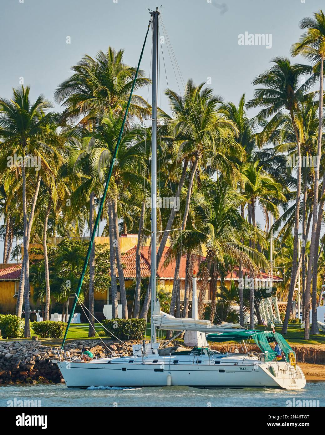 sunset on the beach where a yellow sailboat is passing by in the middle ...