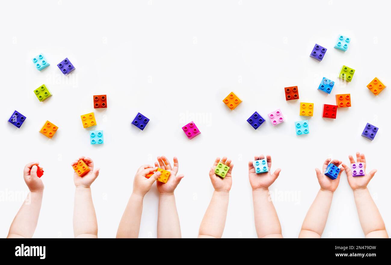 Children hold rainbow colored constructor blocks in fists. Kids hands ...