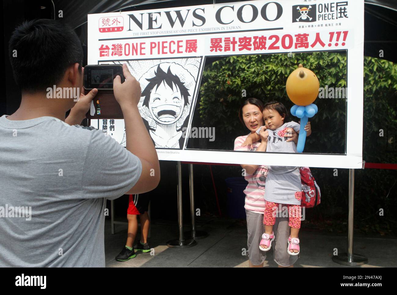 Visitors pose for souvenir photos with a comic character created by ...