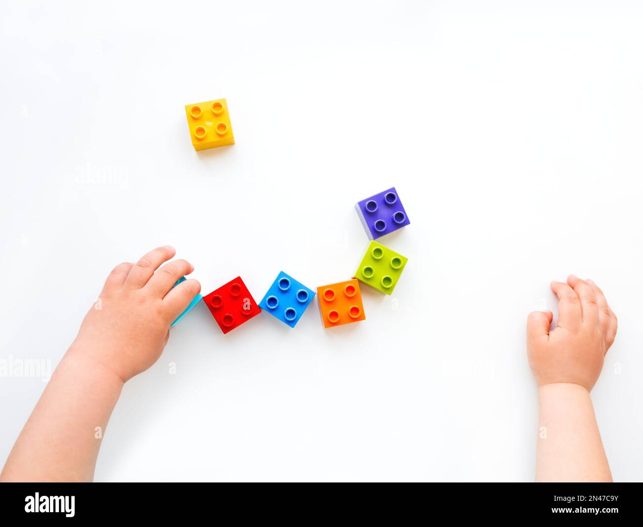 Child is playing with colorful constructor blocks. Kid's hands with ...